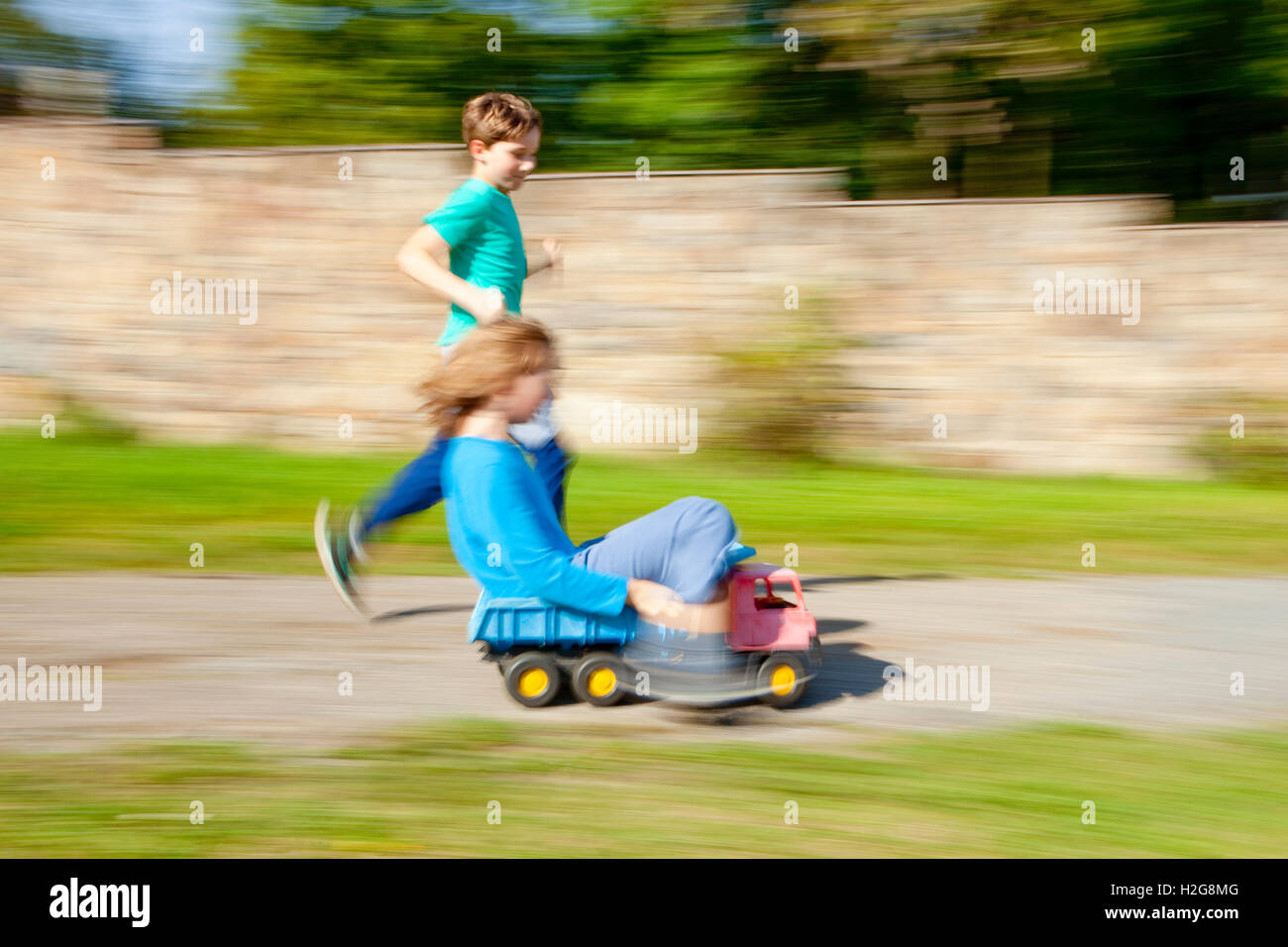 Two Boys Riding Downhill on Top of Toy Lorry Stock Photo - Alamy
