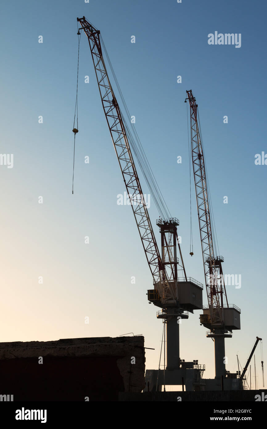 Silhouette of Cranes at Work in Boatyard and Blue Sky in background ...