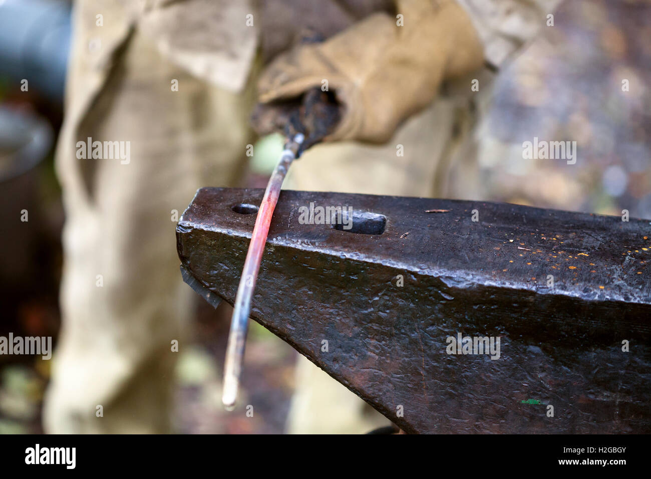 red hot glowing iron rod on anvil in outdoor rural smithy Stock Photo ...