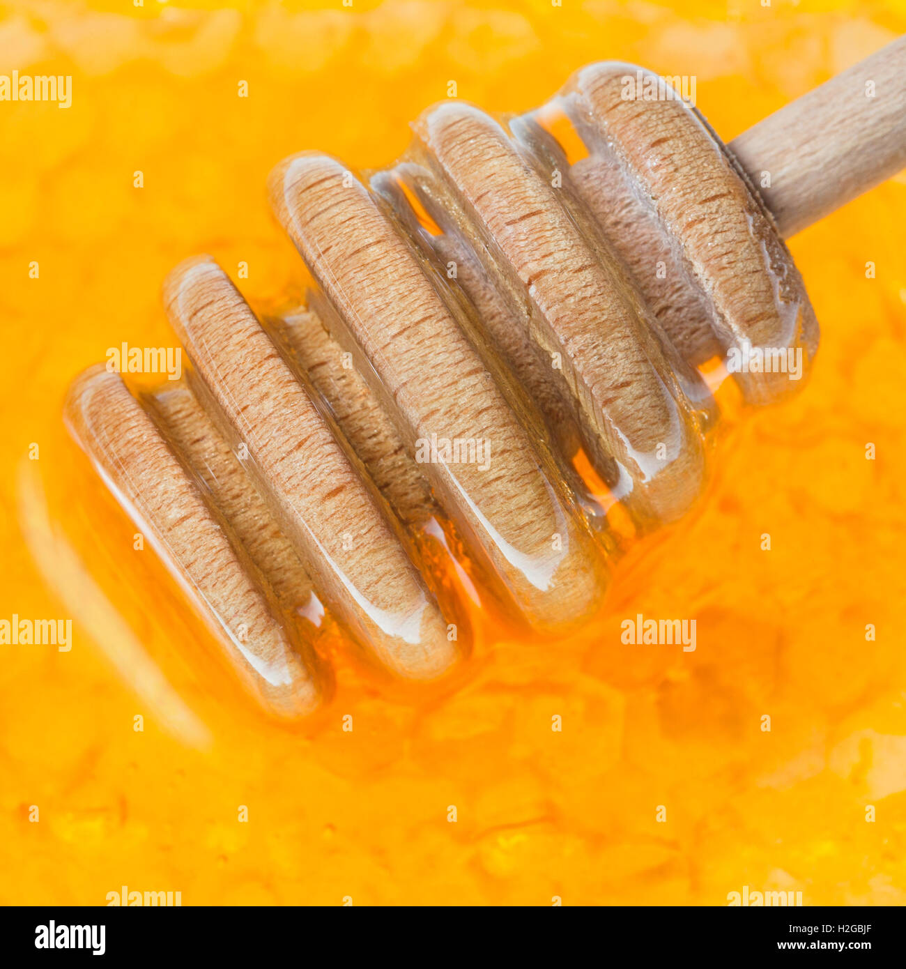 wooden honey dipper on surface of honeycomb with honey close up Stock ...
