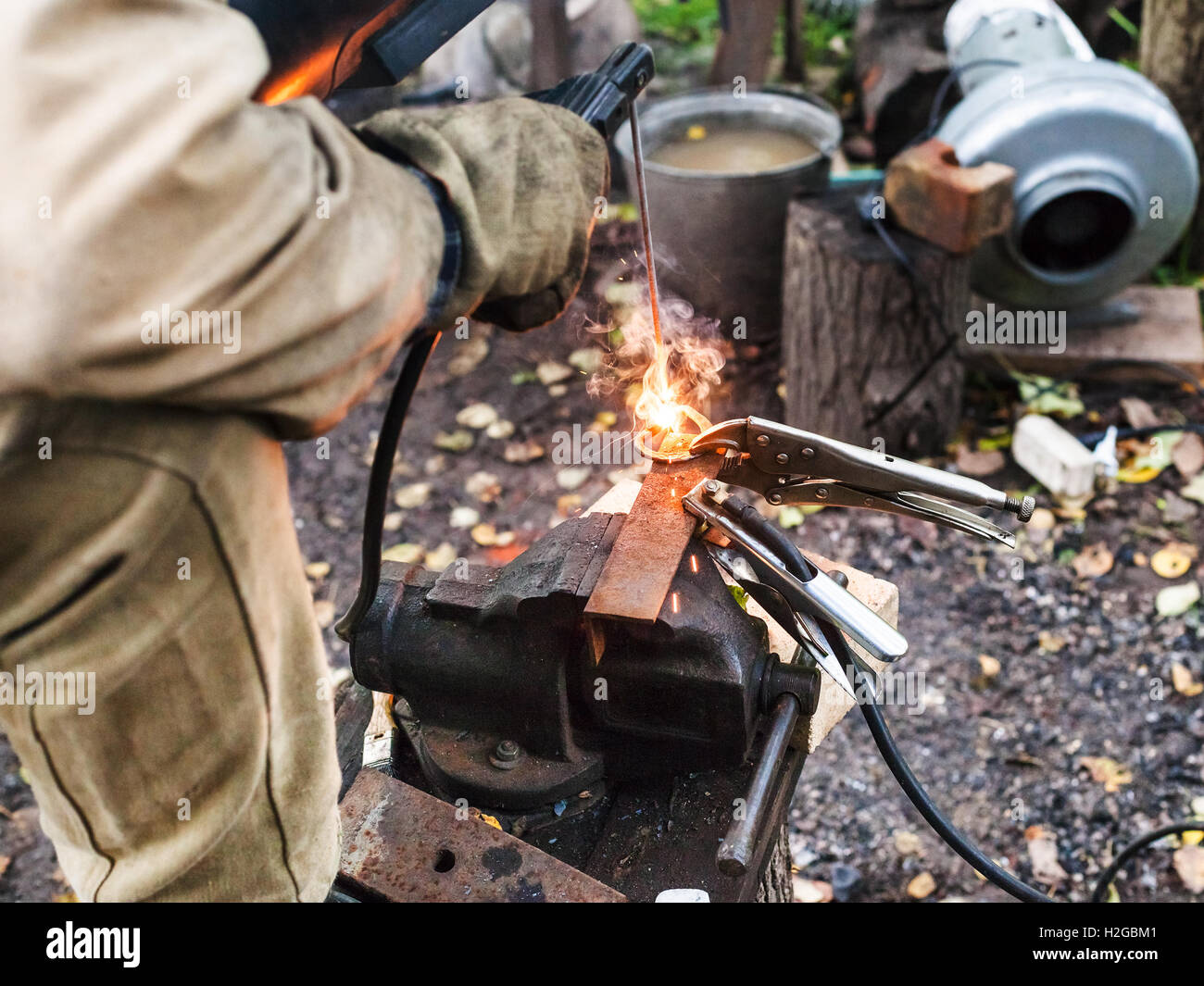 Welder welds steel buckle by spot electric welding in outdoor rural ...