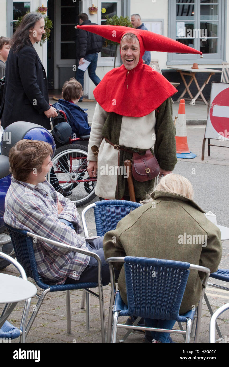 In a Suffolk market town a jester entertains people sitting at a ...