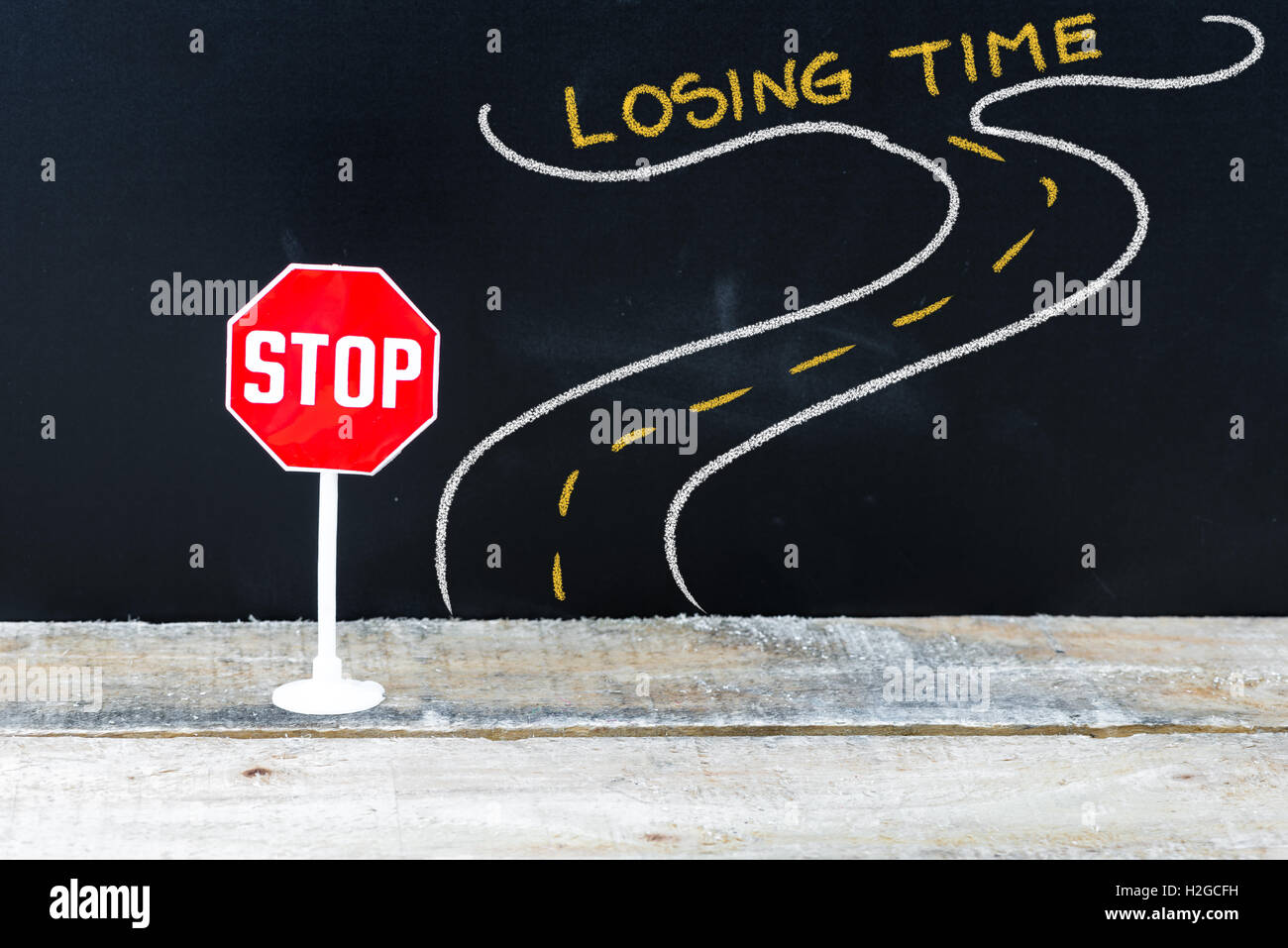 Mini STOP sign on the road to LOSING TIME, hand drawing over chalkboard ...