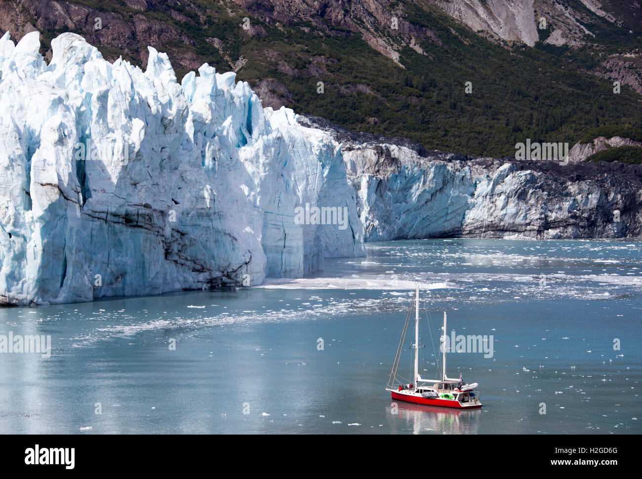 Small tourist boat getting closer to the glacier in Glacier Bay ...