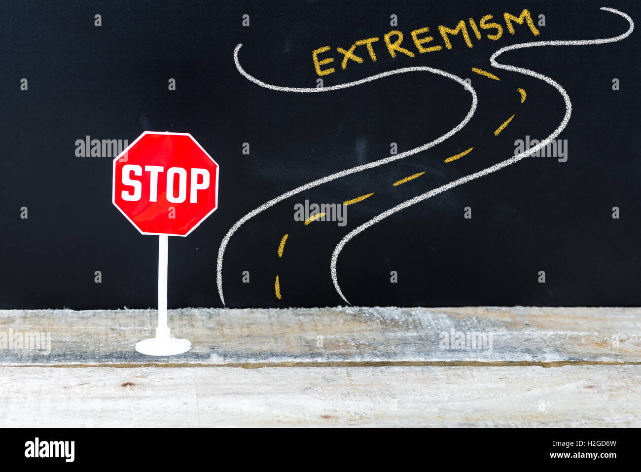 Mini STOP sign on the road to EXTREMISM, hand drawing over chalkboard ...