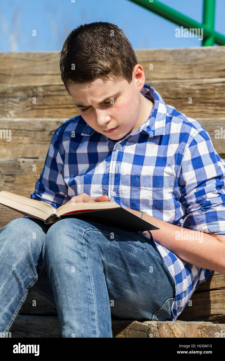 Leisure.Young boy reading a book in the woods with shallow depth Stock ...