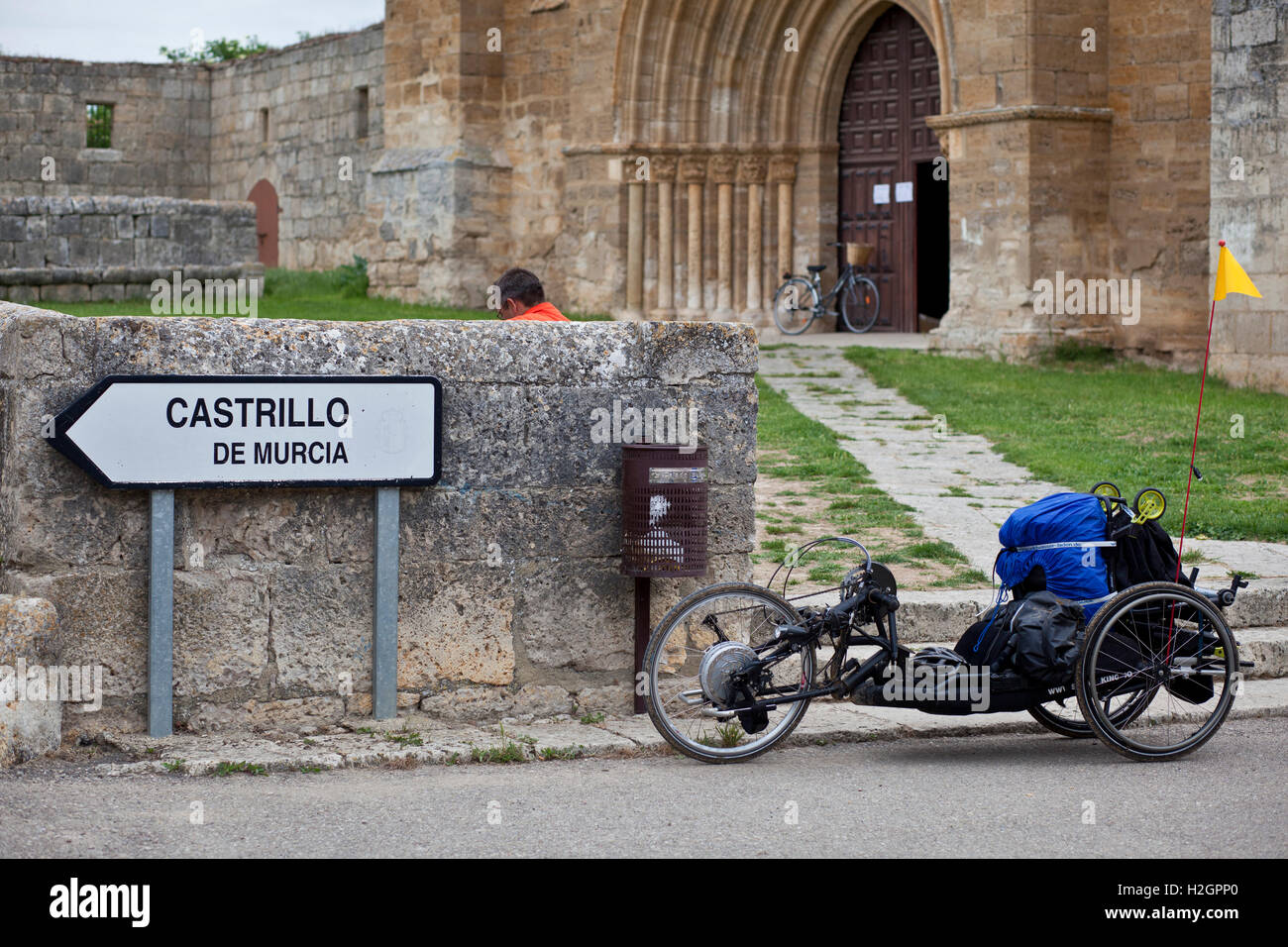 Pilgrim with bike resting outside a church along the Camino de Santiago ...