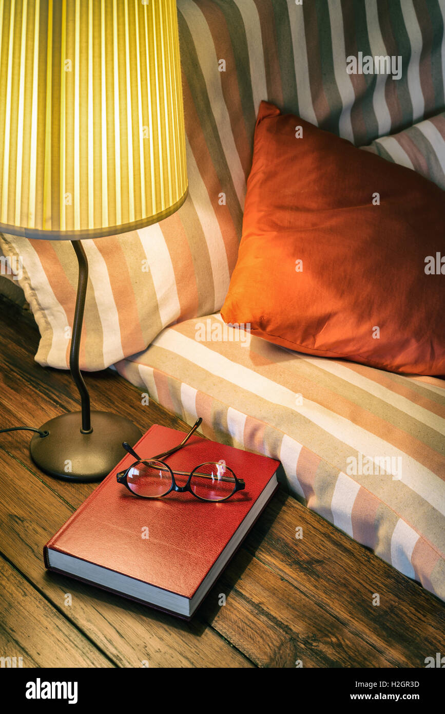 Book and glasses on a table beside a couch. Living room interior and ...