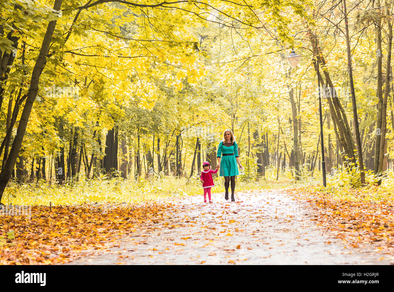 Mother and daughter walking holding hands at park. Family lifestyle, autumn season concept Stock ...