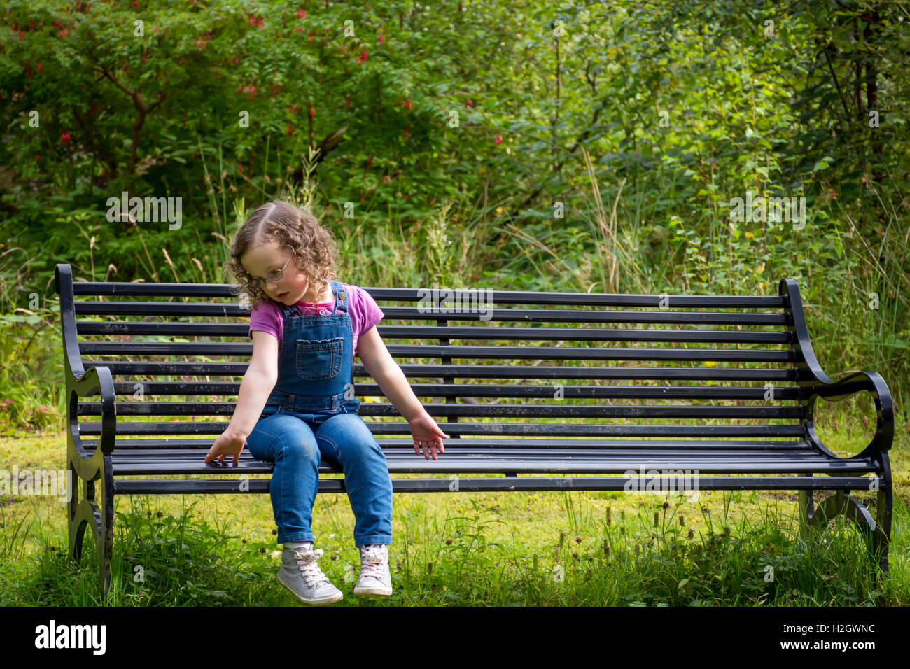Little girl sitting on a park bench Stock Photo - Alamy