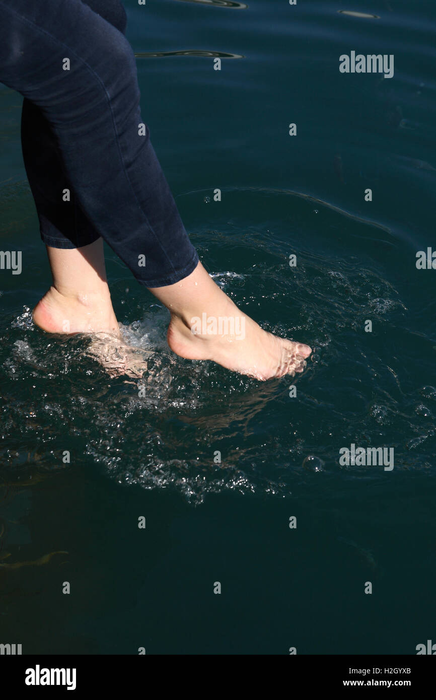 Closeup of female feet splashing sea water Stock Photo - Alamy
