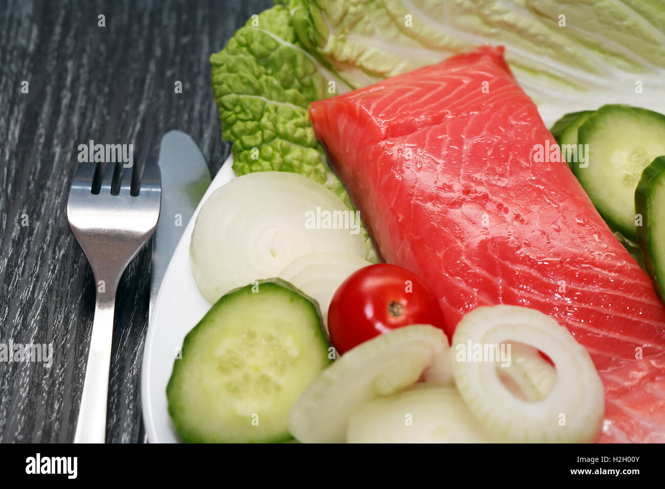 Closeup of filleted trout on plate near various vegetables Stock Photo ...