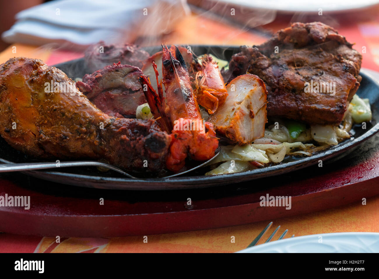 A dish of indian food at a restaurant. Steam coming of the plate which ...
