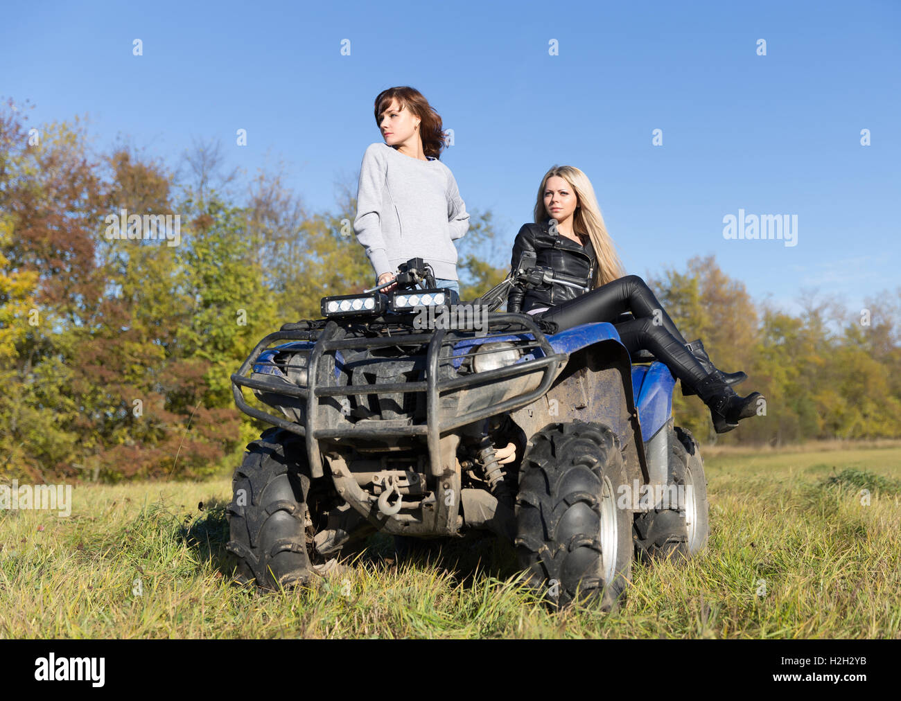 Two elegant women riding extreme quadrocycle ATV field Stock Photo - Alamy