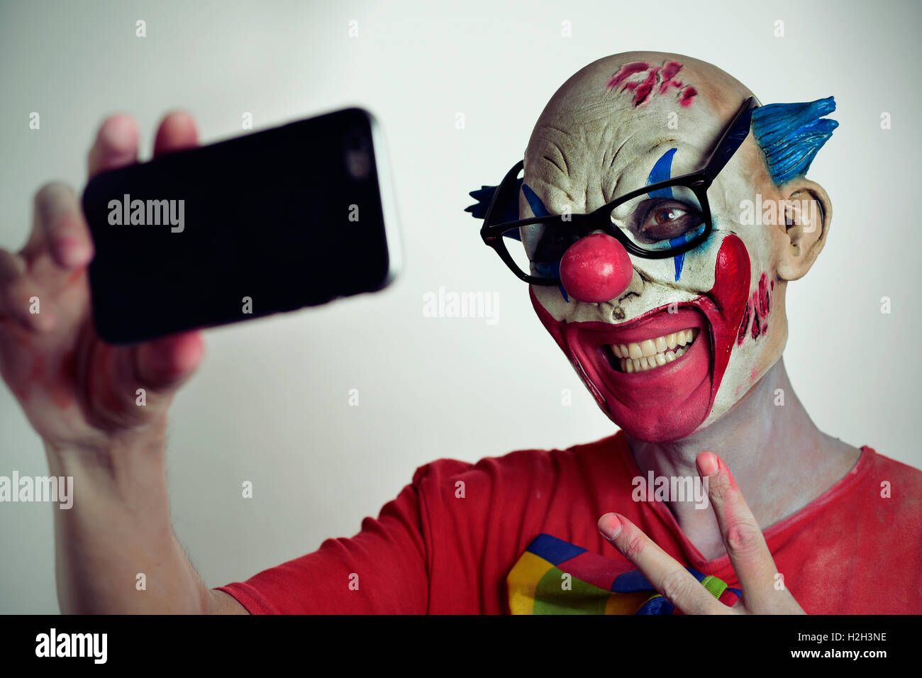 portrait of a scary evil clown taking a selfie with his smartphone ...