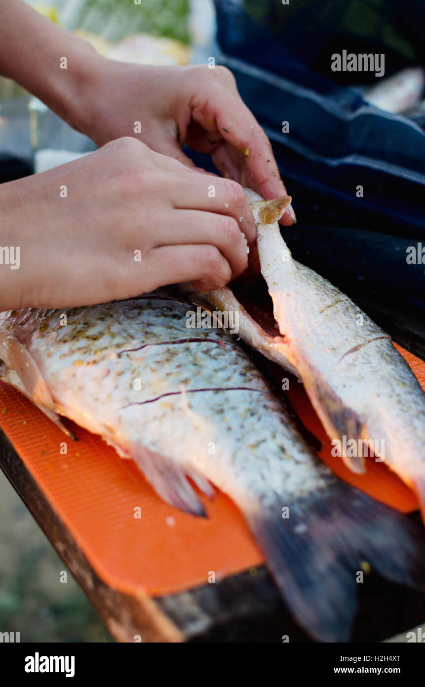 Woman cut up the fish and put spices inside big freshly caught and ...