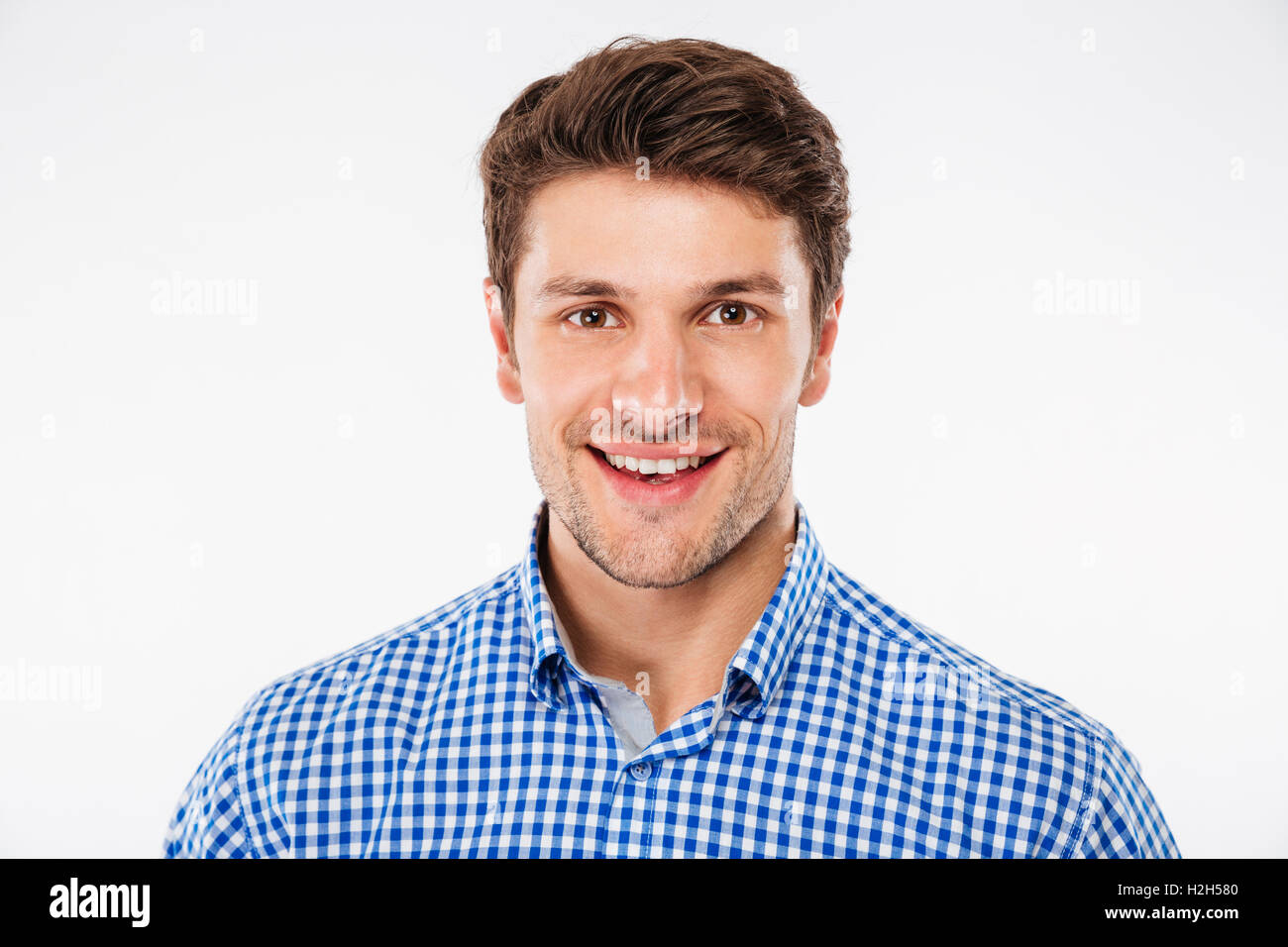 Portrait of cheerful attractive young man in checkered shirt over white ...