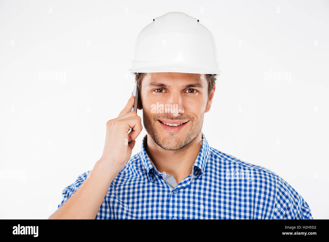 Happy young man building engineer in helmet talking on mobile phone ...