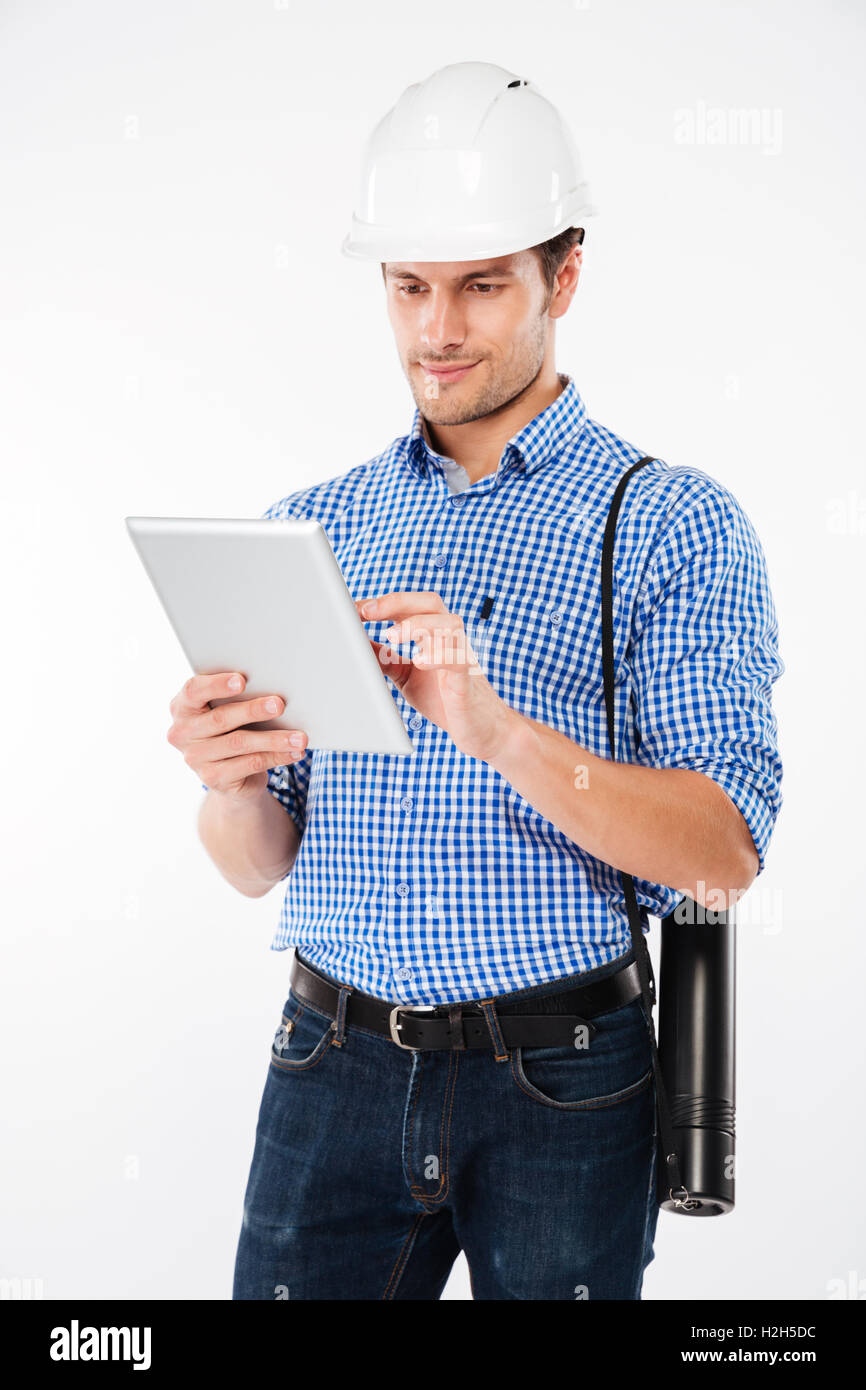 Concentrated young man building engineer in hard hat standing and using ...