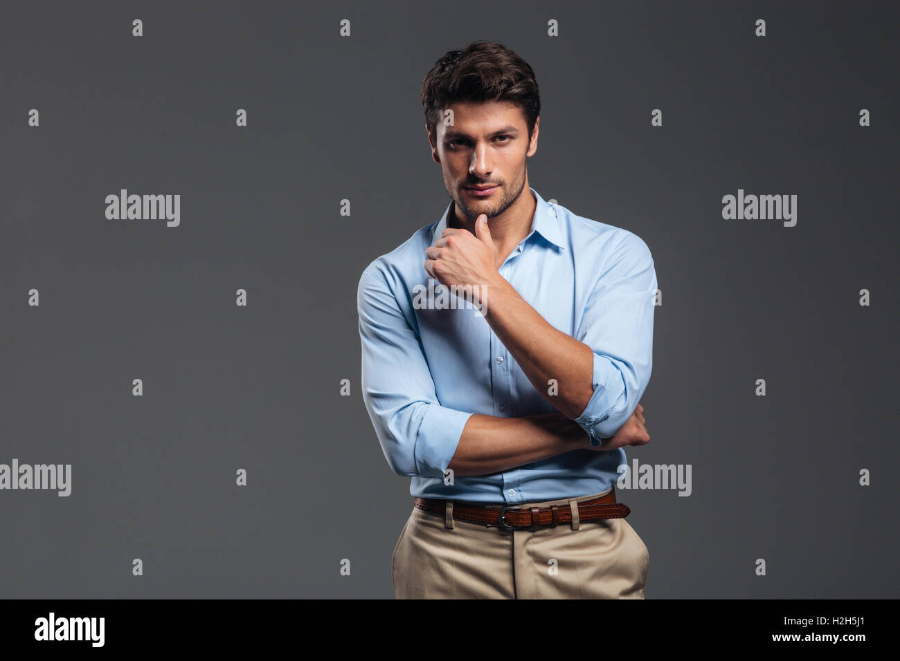 Handsome serious man looking at camera isolated on a gray background ...