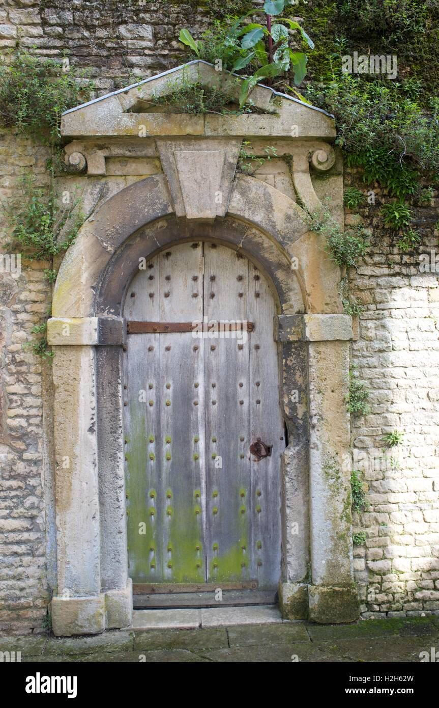 Studded rustic wooden door in stone wall with decorative surround and ...