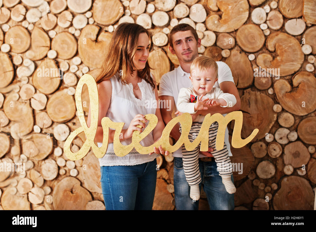 Young caucasian happy family background wooden stump wall with word ...