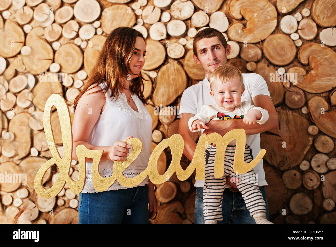 Young caucasian happy family background wooden stump wall with word ...