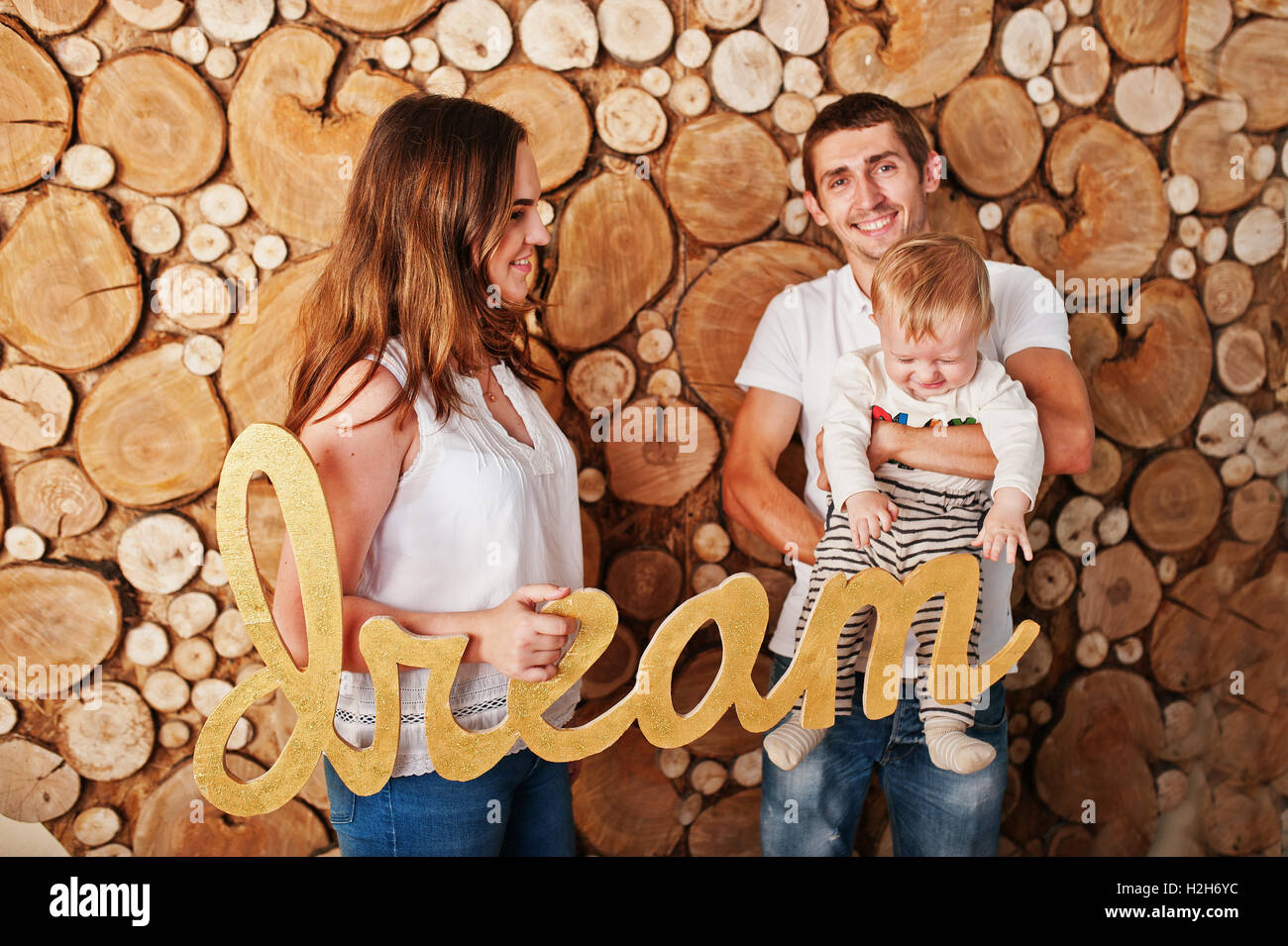Young caucasian happy family background wooden stump wall with word ...