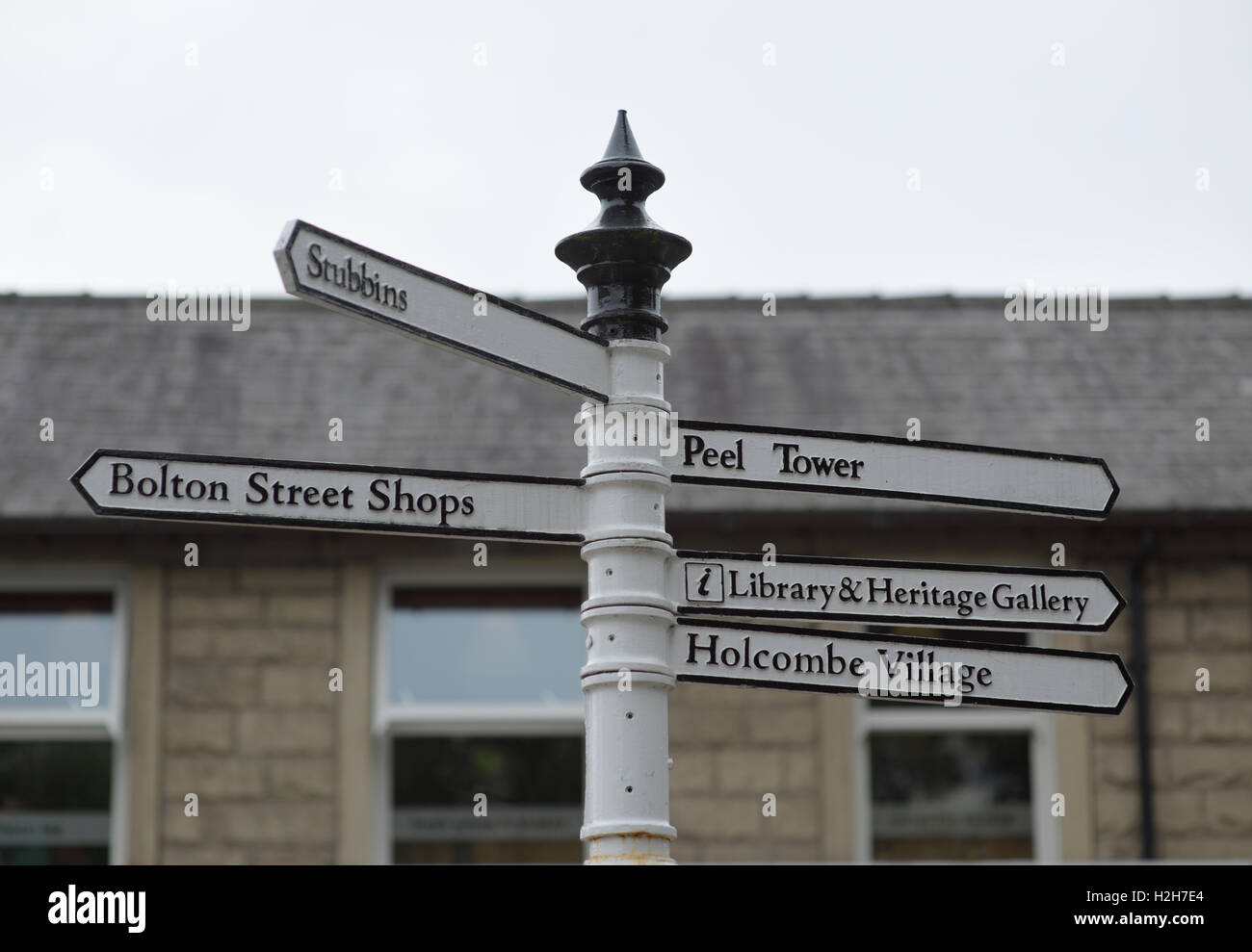Cast iron fingerpost signage with five finger arms and blurred building ...