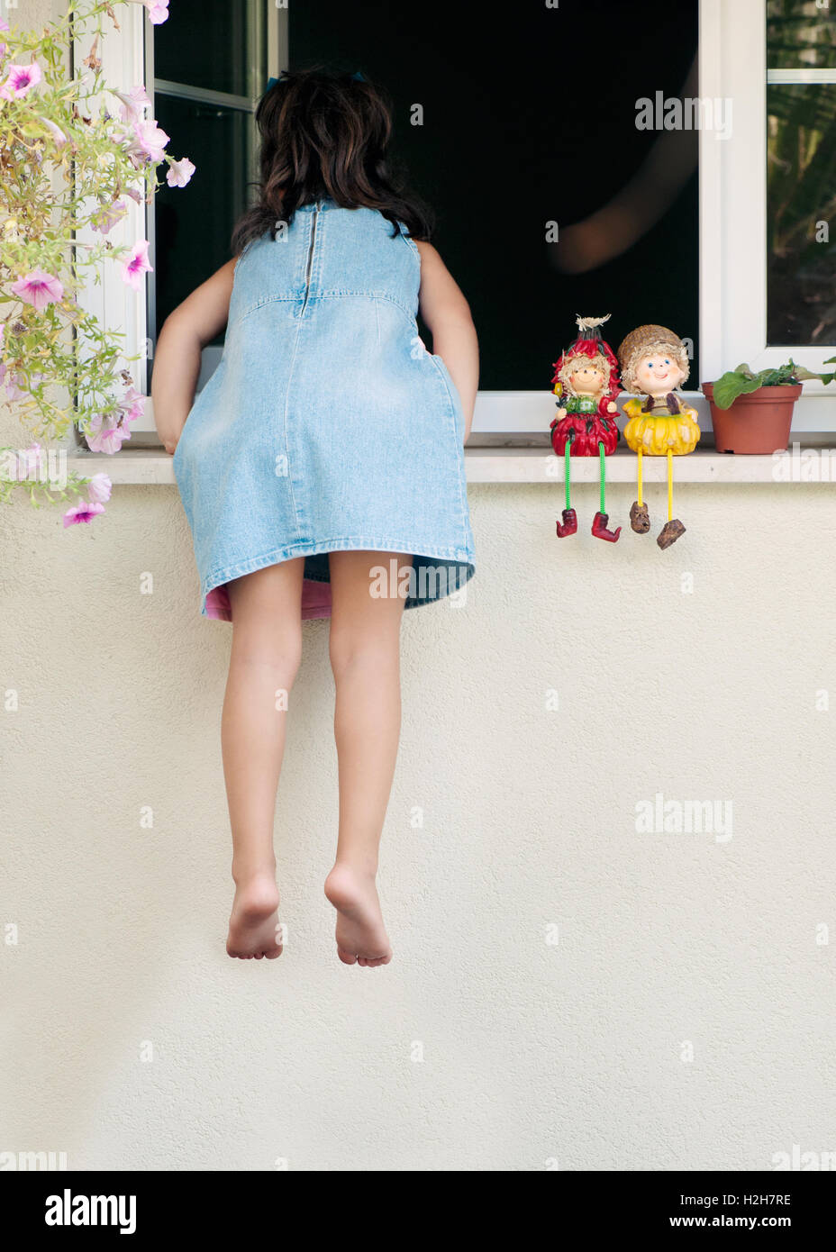 Little girl climbing out of window Stock Photo - Alamy
