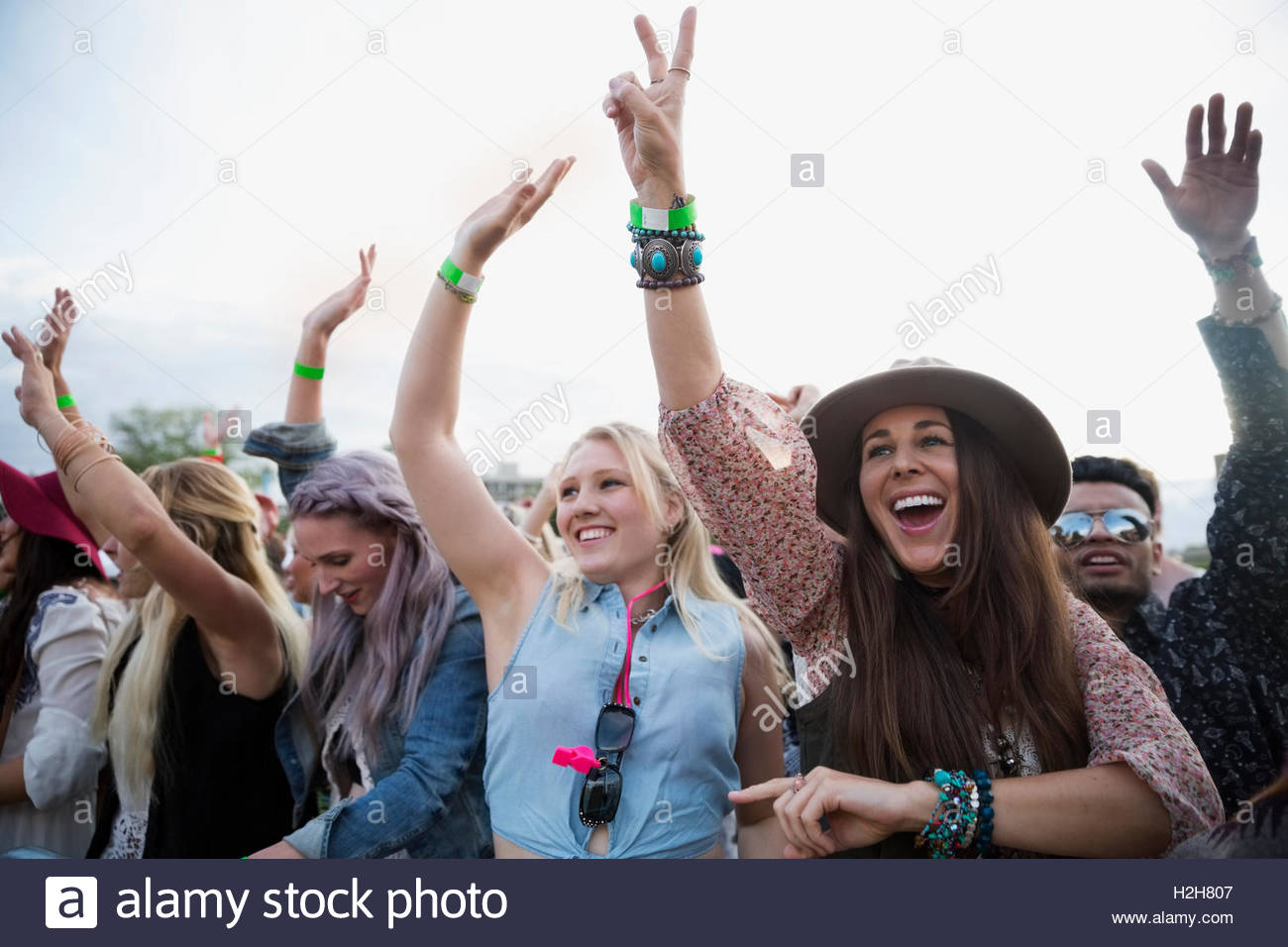 Enthusiastic young women cheering in crowd at summer music festival ...