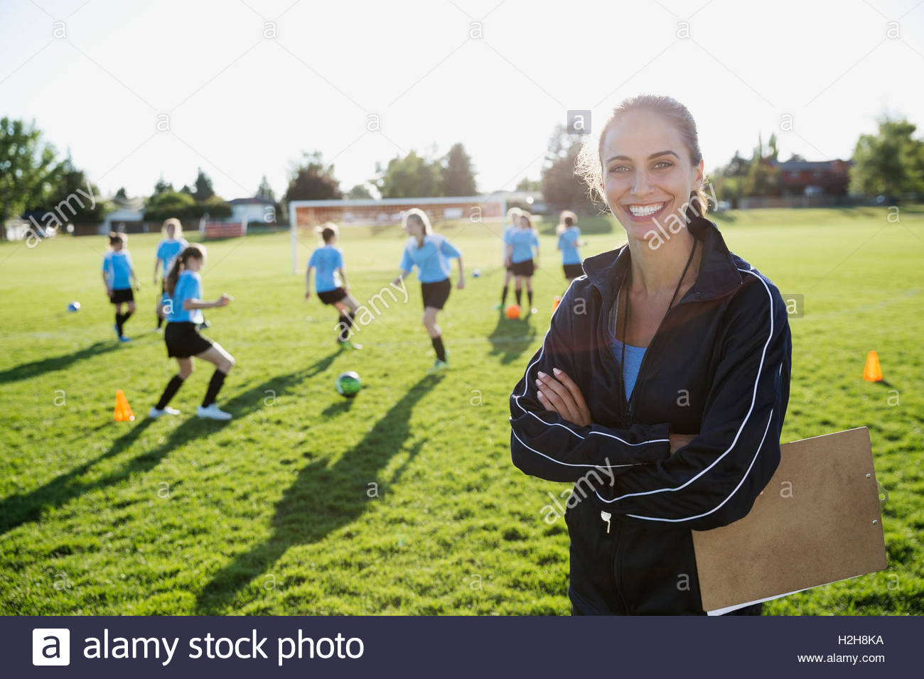 Portrait confident coach and middle school girl soccer team running ...