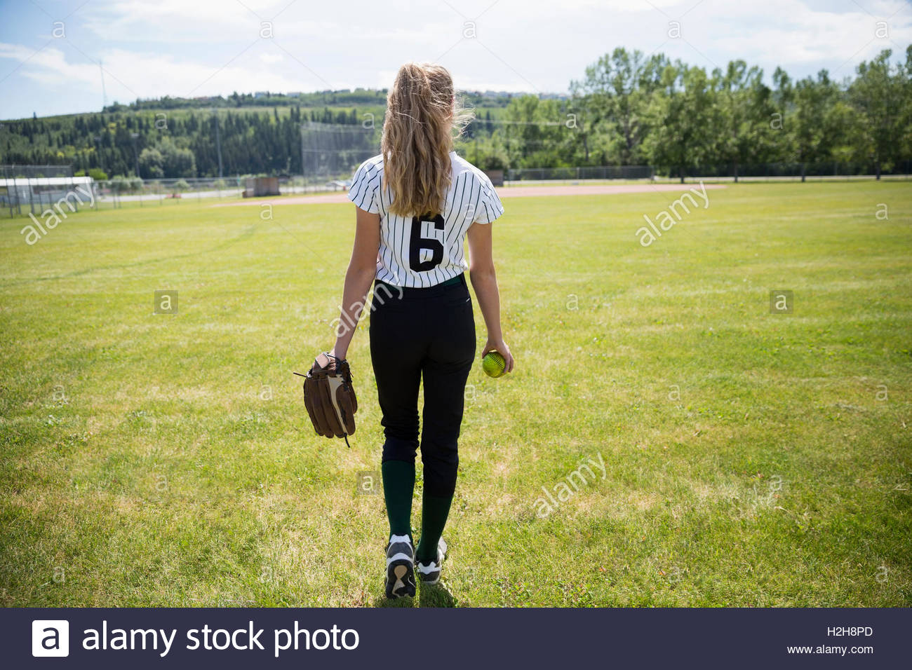 Middle school girl softball player walking in sunny outfield Stock ...