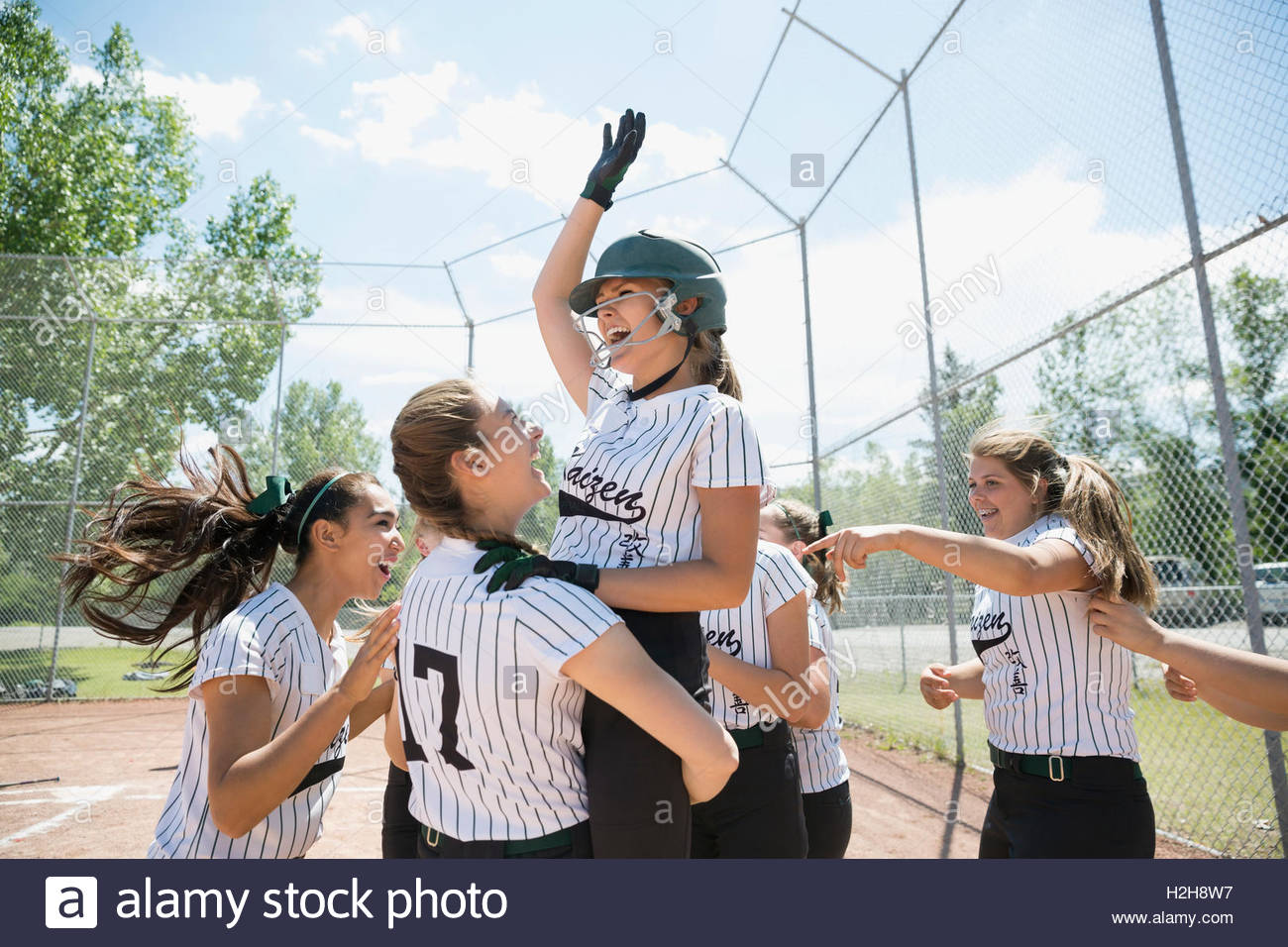 Enthusiastic middle school girl softball team celebrating on baseball ...