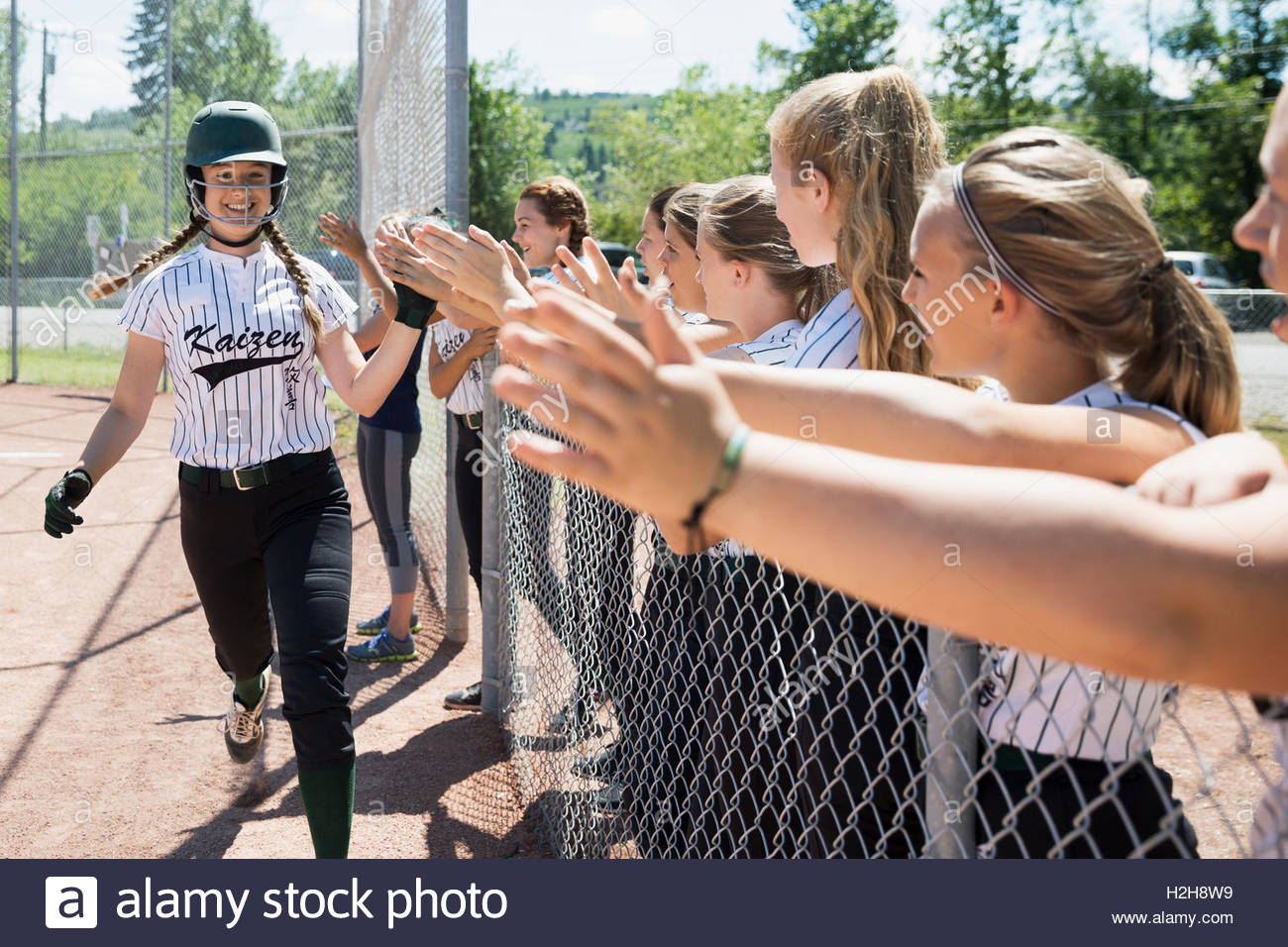 Middle school girl softball team high fiving teammate over fence Stock ...