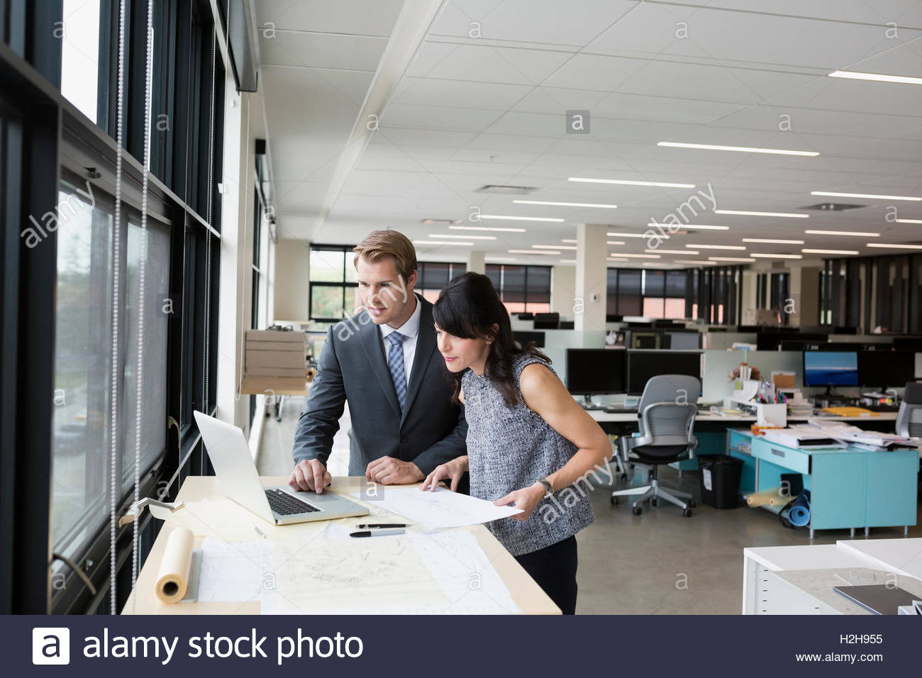Architects working with blueprints at laptop in office Stock Photo - Alamy