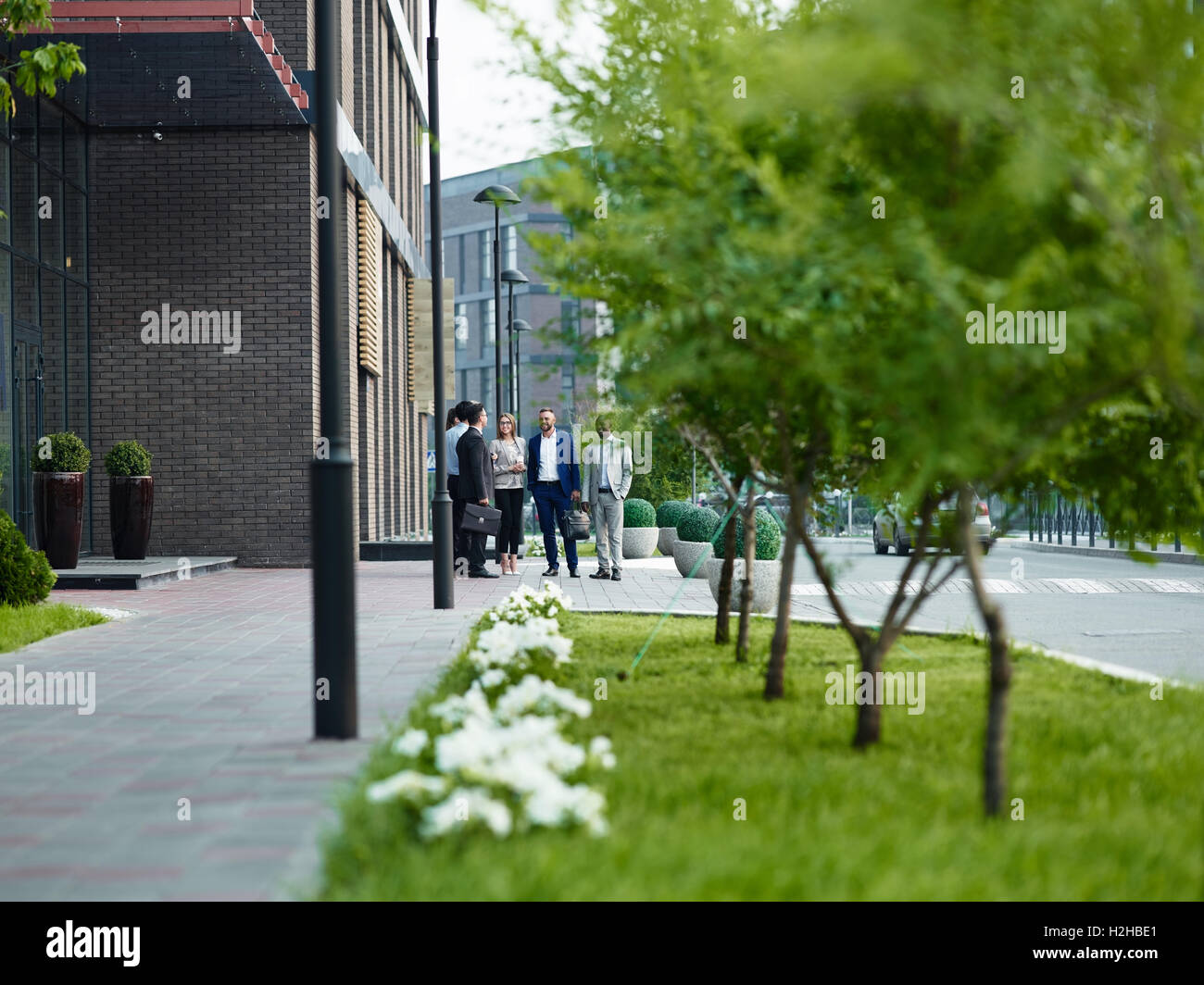 Young employees communicating outdoors by modern office building Stock ...