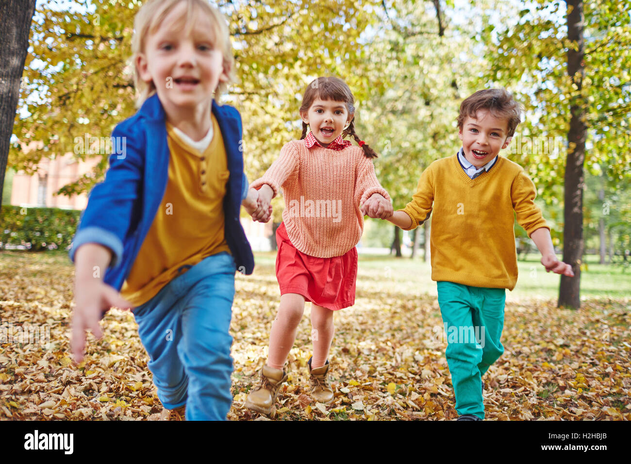 Happy kids running in park in autumn Stock Photo - Alamy