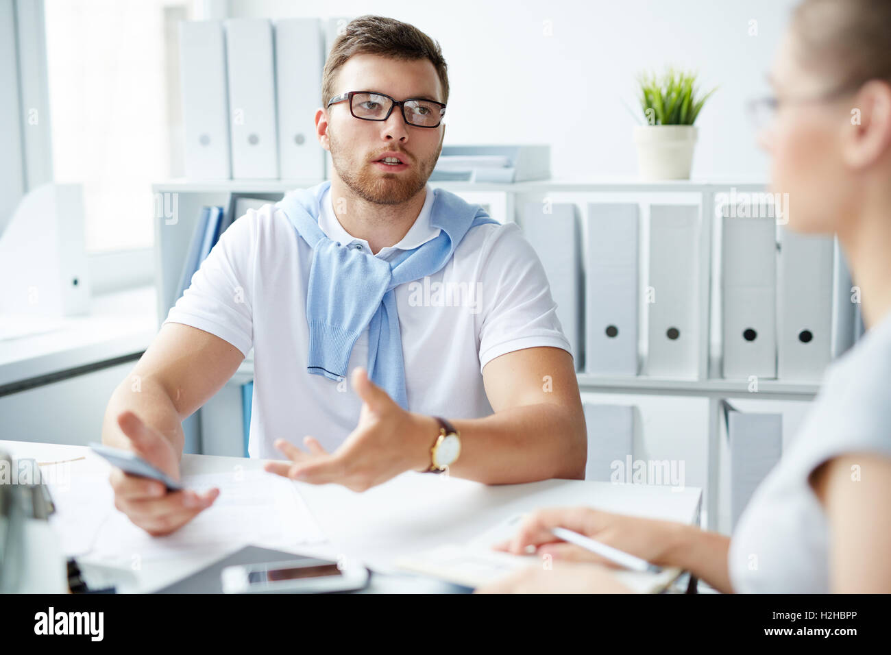 Young man explaining new project to colleague in office Stock Photo - Alamy
