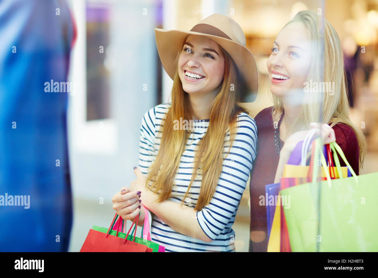 Two stylish shopaholics looking through shop-window Stock Photo - Alamy