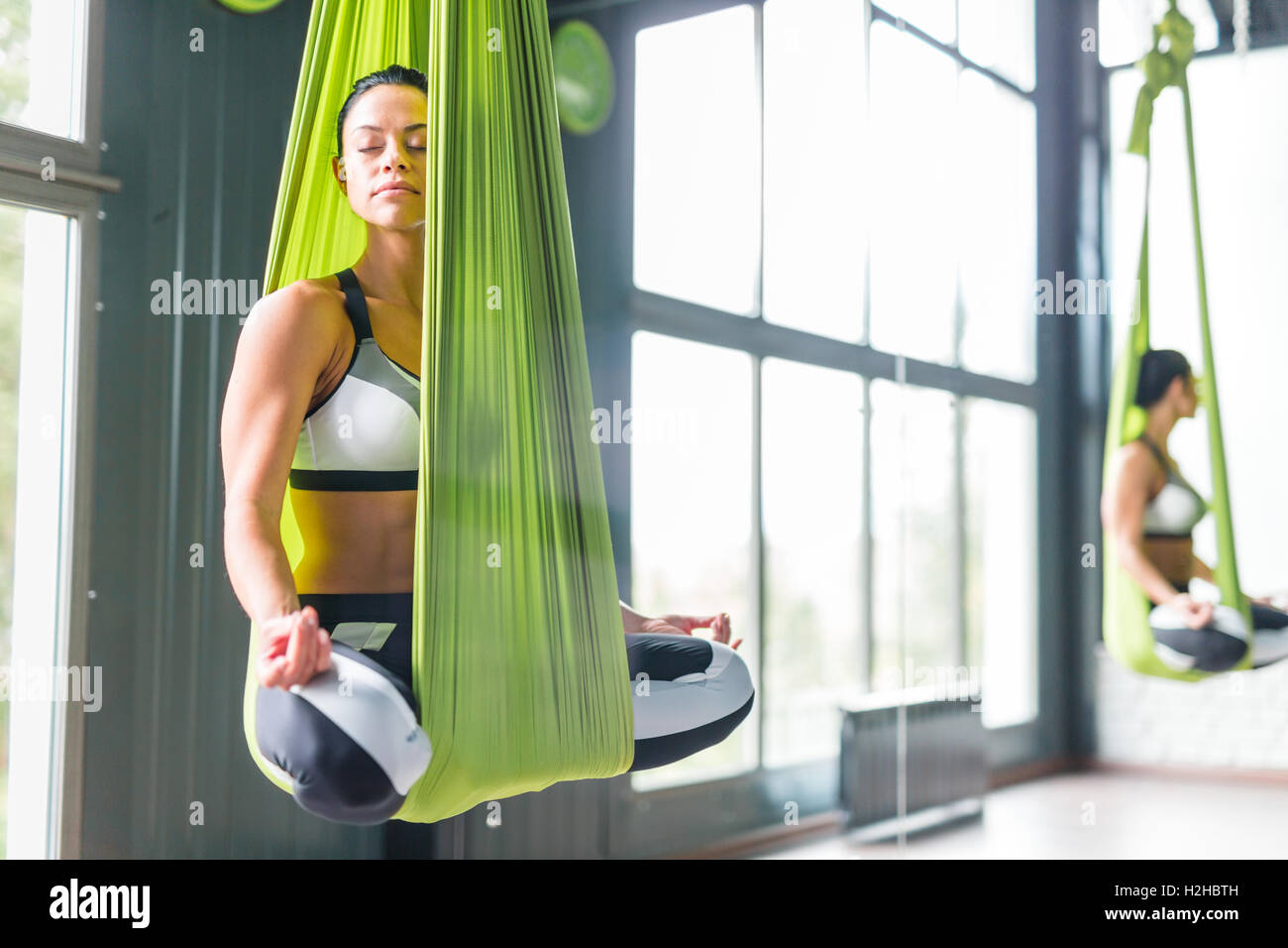 Young woman relaxing in hammock in pose of lotus in gym Stock Photo - Alamy