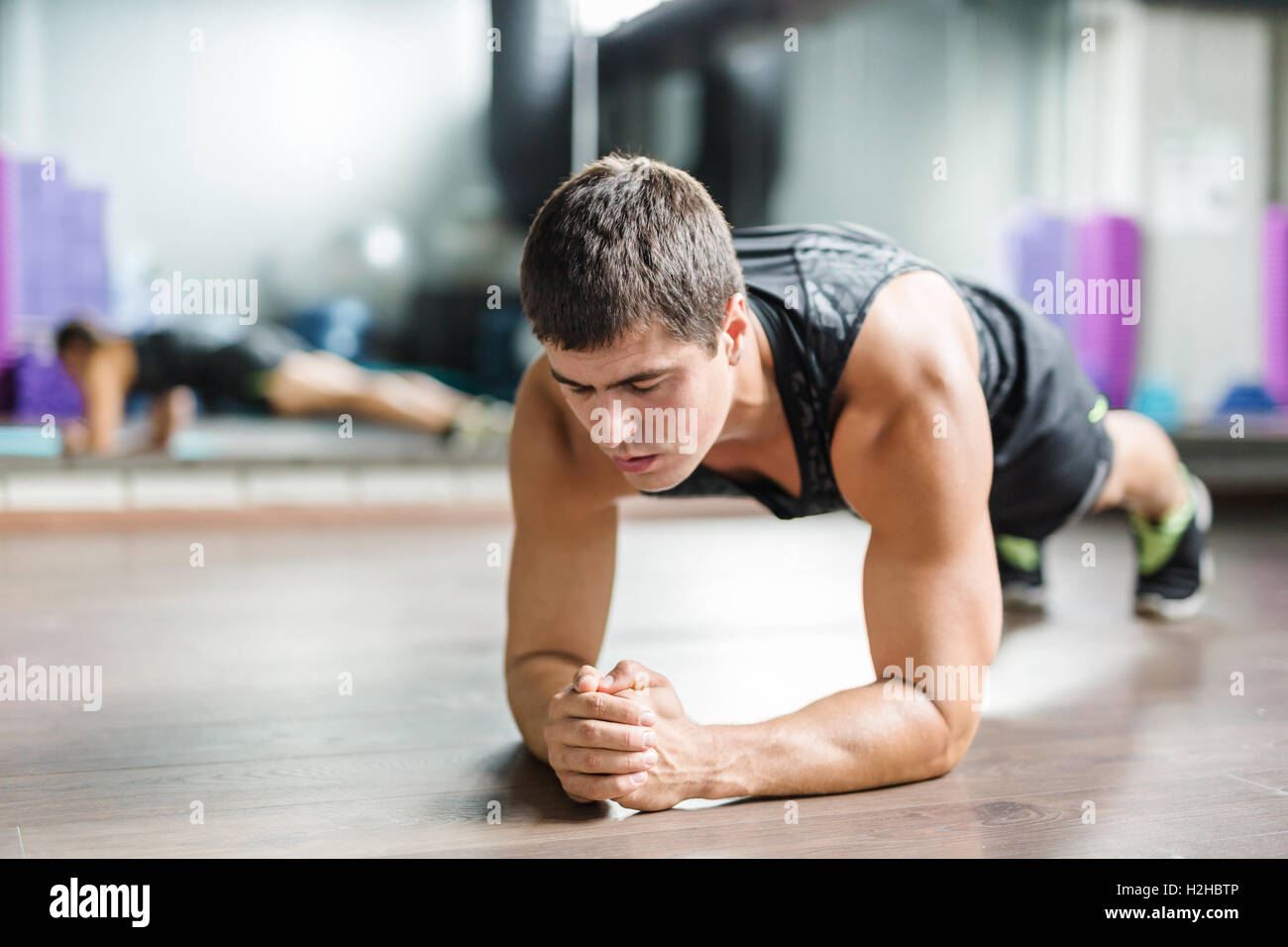 Muscular young man doing planks on the floor of gym Stock Photo - Alamy