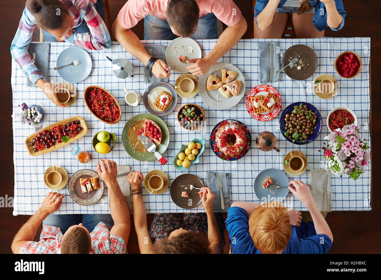Young people eating festive dinner by served table Stock Photo - Alamy