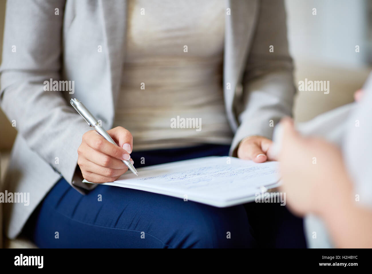 Psychologist making notes during talk with patient Stock Photo - Alamy