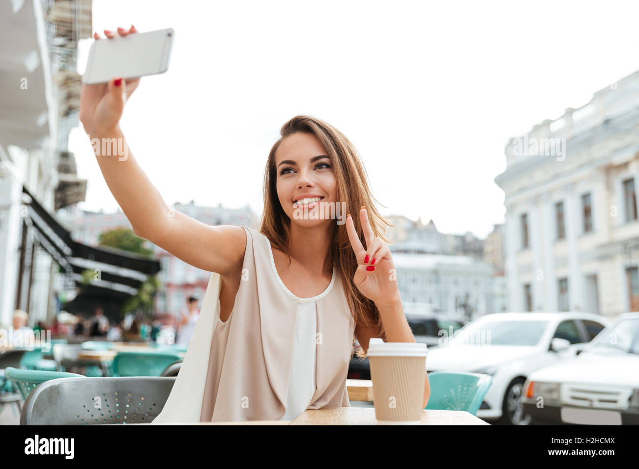Happy smiling beautiful girl making selfie and showing victory sign ...