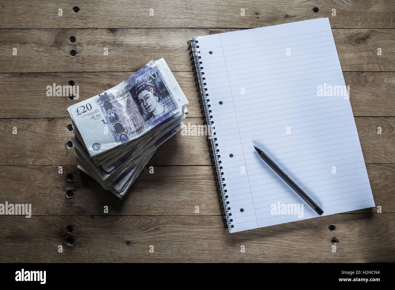 Pile of twenty pound notes and a lined A4 writing pad and pen Stock ...