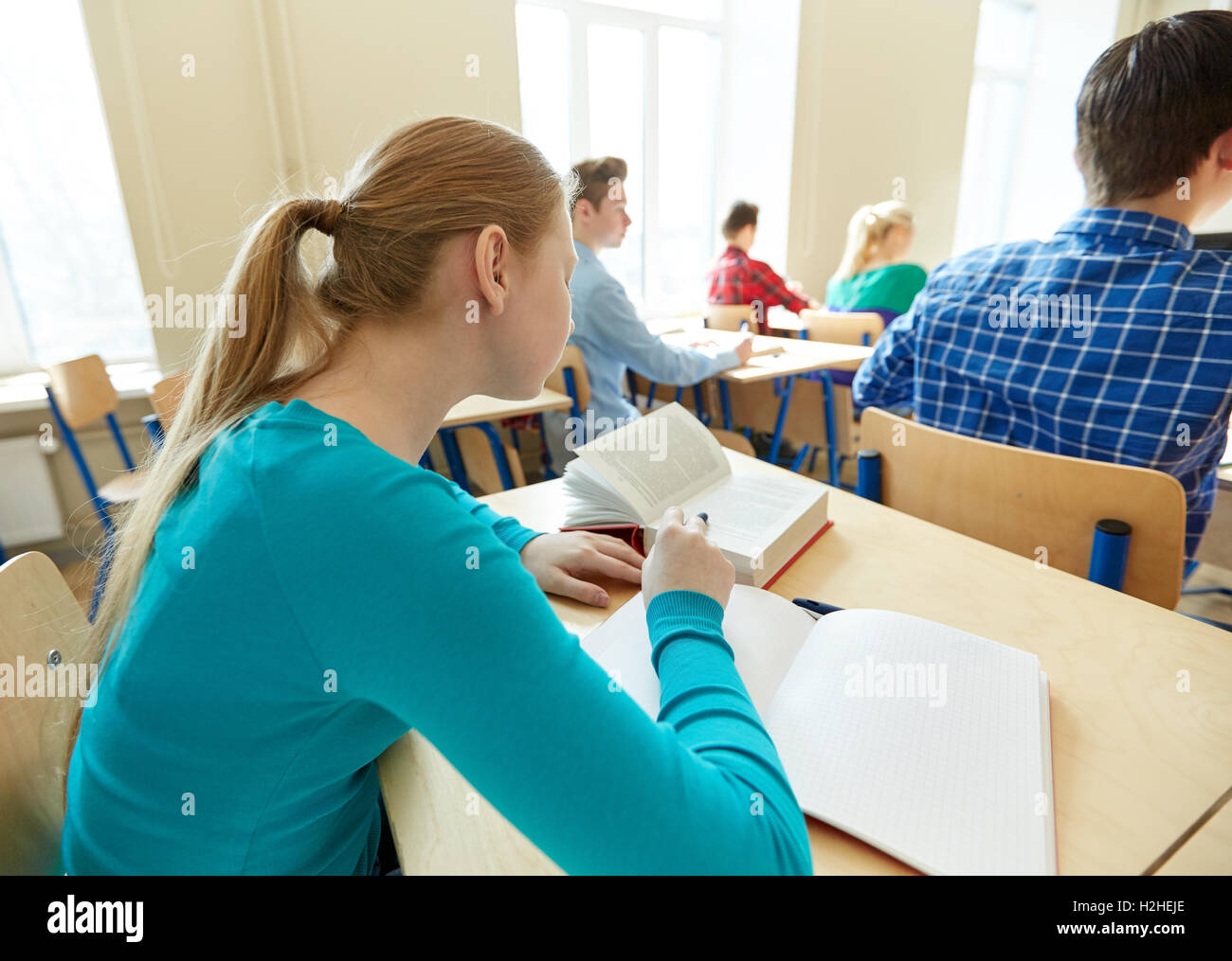 group of students with books writing school test Stock Photo - Alamy