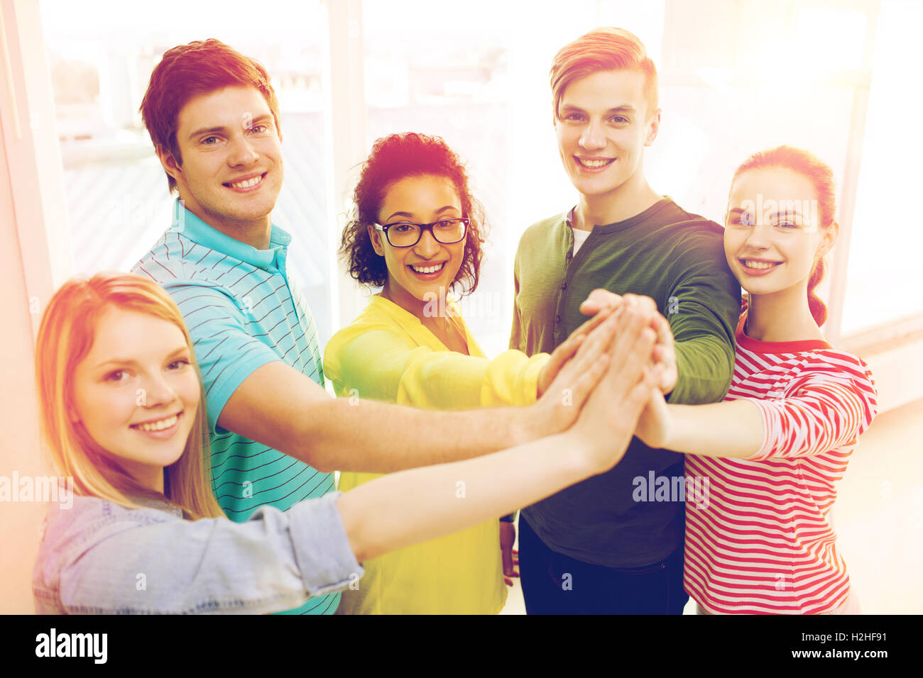 five smiling students giving high five at school Stock Photo - Alamy