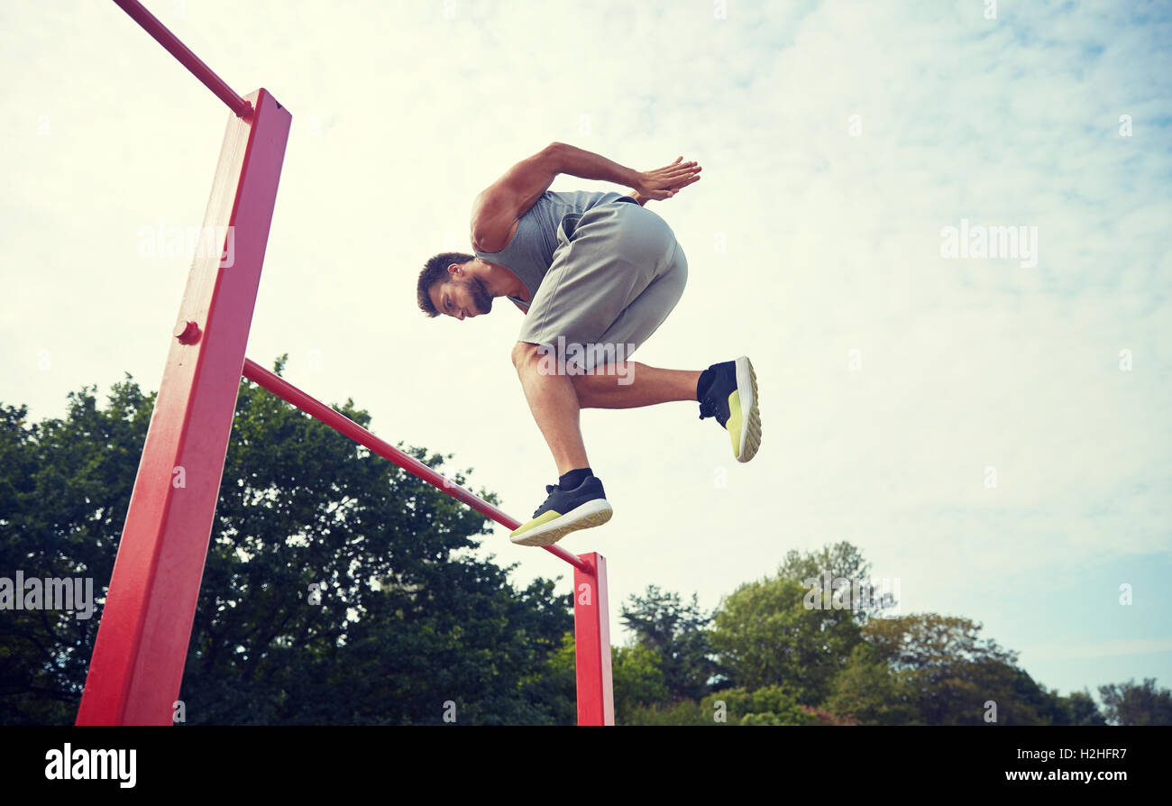 young man jumping on horizontal bar outdoors Stock Photo - Alamy