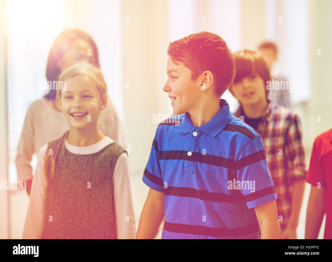 group of smiling school kids walking in corridor Stock Photo - Alamy